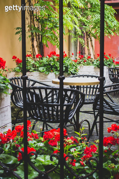 Cozy street cafe with iron fence in old town. Empty patio with outdoor ...