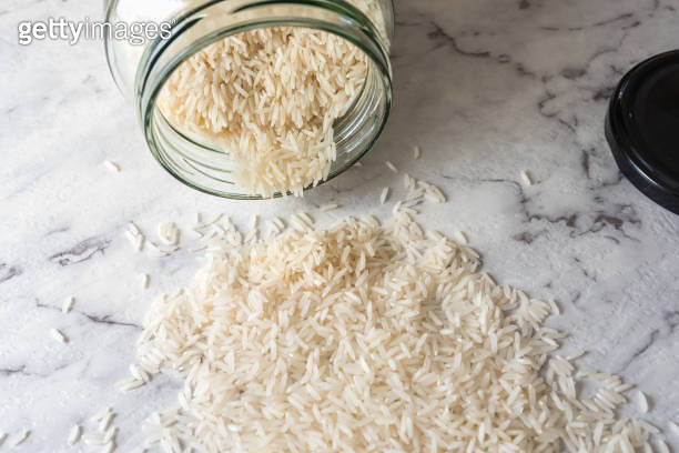 Fallen glass jar with basmati rice spilled in foreground (1348683634 ...