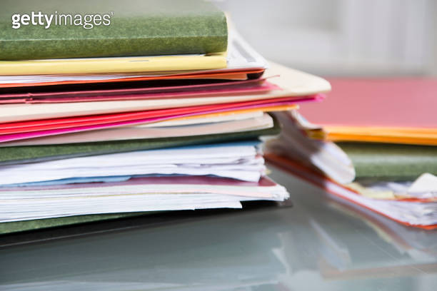 Stack of file folders with documents on a glass top desk. 이미지 ...
