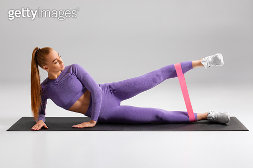 Fitness woman doing leg raises exercise for glute with resistance band ...