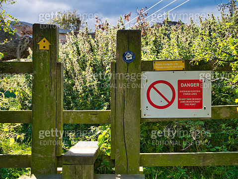 A red and white warning sign on a stile on the Northumberland Coast ...
