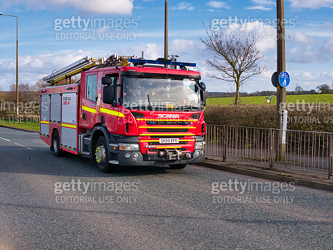 A red Scania fire engine on an urban road in the UK, taken in winter ...