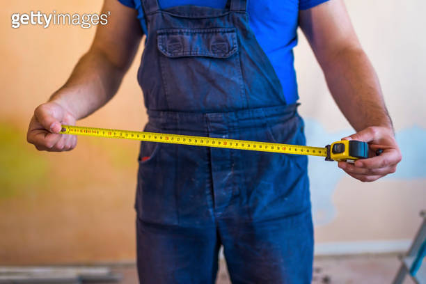 Workman in overalls with a tape measure in his hands 이미지 (1318490961 ...
