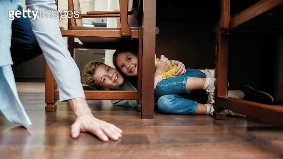 Two little kids siblings playing hide and seek game with grandfather at ...
