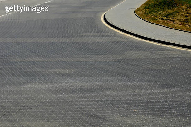 road surface in a bend with sidewalk on the side. the concrete paving ...