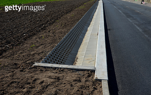 on the side of the road there is a concrete wall support and a ditch ...