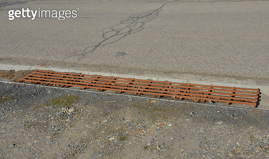 at the edge of the road is a concrete trough for collecting rainwater ...