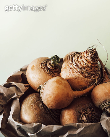 fresh turnips in a crumpled paper bag on a light table. turnip sprigs ...