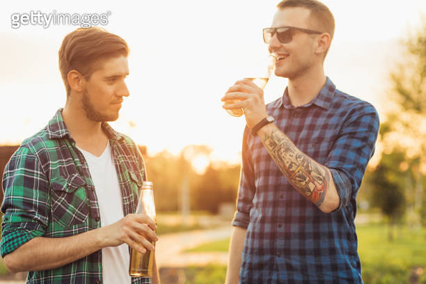 Two young male friends walking in the park in summer on a sunny day ...