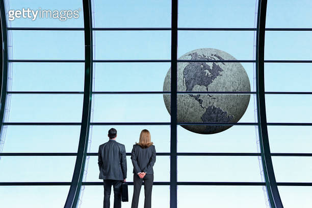 Man And Woman Look Out Window As Globe Showing Western Hemisphere Hangs ...