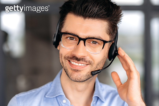Close-up portrait of handsome satisfied man, operator of call center or ...