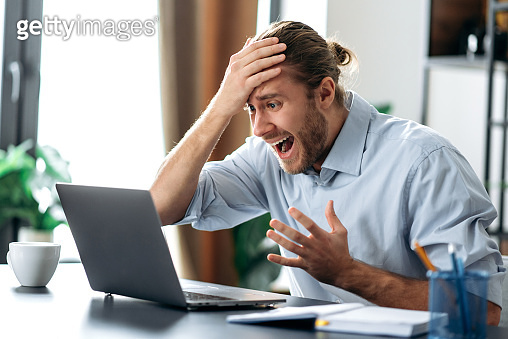 Shocked annoyed caucasian busy guy looking at a laptop in confusion ...