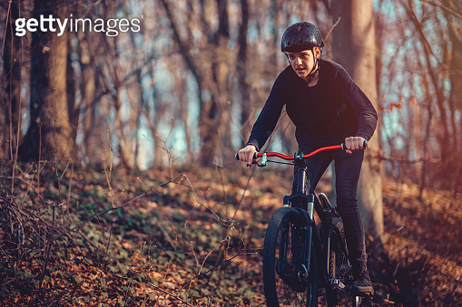 Teenage boy riding mountain bike through forest 이미지 (1349812336) - 게티이미지뱅크