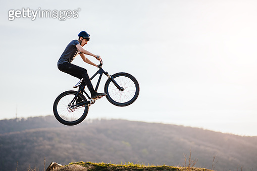 Young man flying through the air on a mountain bike 이미지 (1300047586 ...