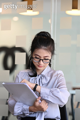Young woman checking time on her watch and waiting for job interview in ...