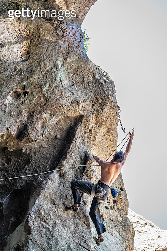 One man climber on a hard move at a steep overhanging rock. Courage ...