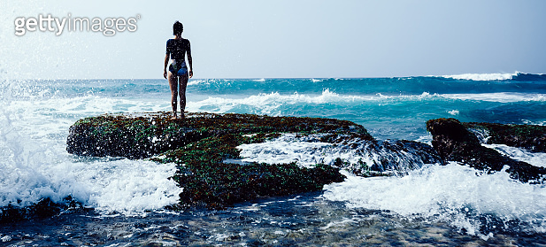 Woman at the seaside cliff edge facing the coming strong sea waves 이미지 ...