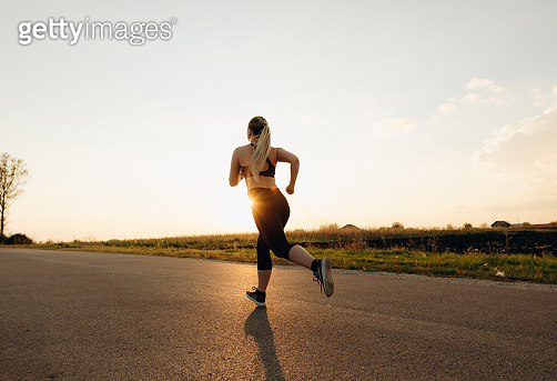 Young sporty girl running on a road at sunset. Lifestyle sports ...