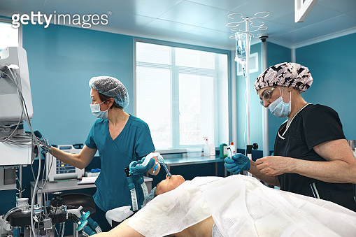 Teams of a doctor in a modern operating room, connects the patient to ...