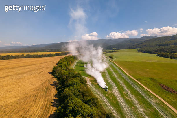 Aerial view of a tractor spreading lime on agricultural fields to ...