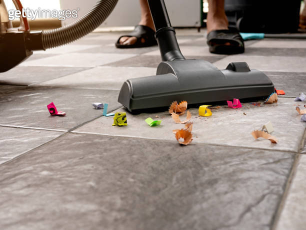 Sweep up paper scraps and dust on tile floors with a vacuum cleaner ...