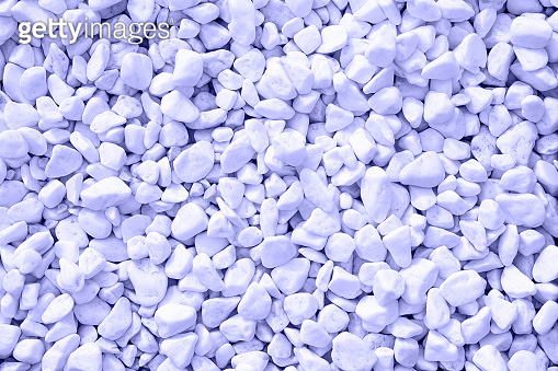 Texture of pure white pebbles tinted in pantone color 2022 very peri ...