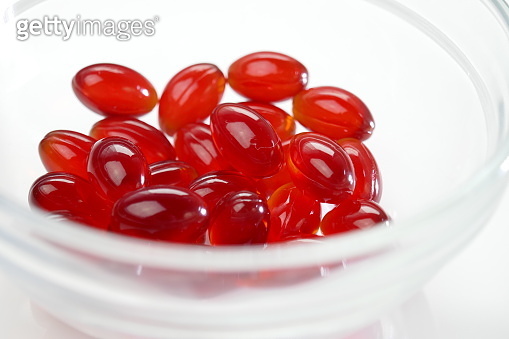 krill oil gelatin capsules in a glass transparent cup on a white ...
