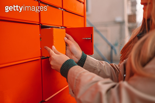 Woman picks up mail from automated self-service post terminal machine ...