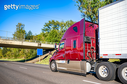 Dark red big rig semi truck with refrigerator semi trailer driving on ...