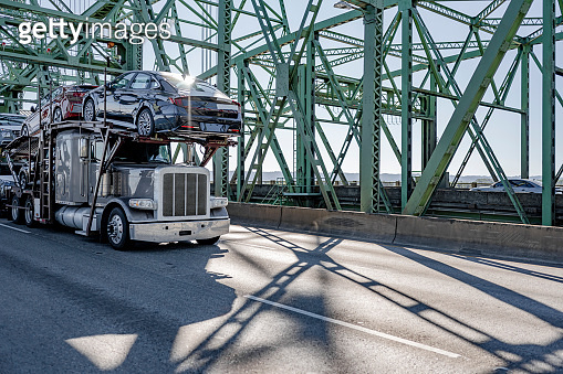 Industrial car hauler big rig gray semi truck transporting cars on ...