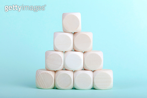 Simple pyramid made of small empty blank wooden blocks, cubes on light ...