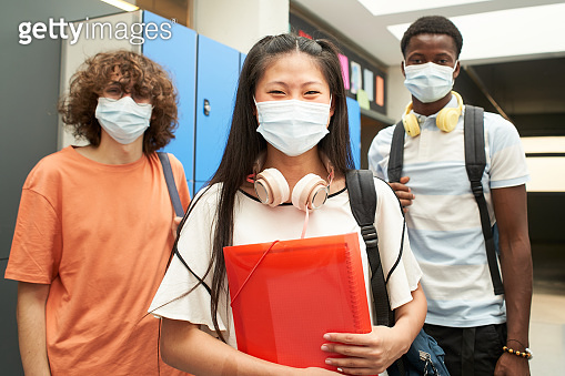 A group of multiracial students with mask looking at camera smiling. At ...