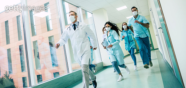 Group of serious and confident doctors in safety medical masks are ...