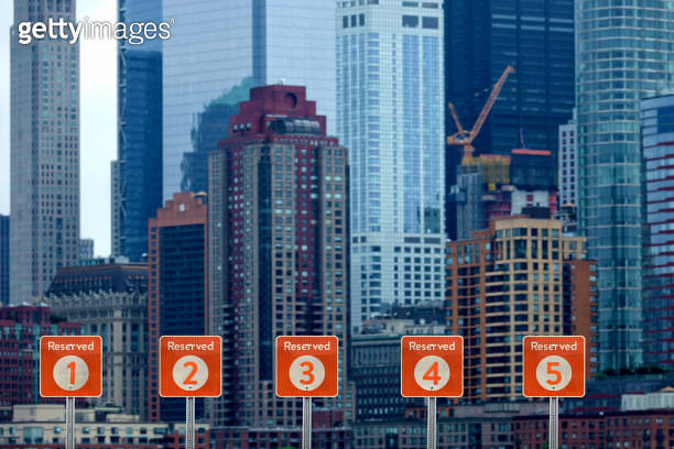 Orange colored reserved signs in parking lot and cityscape view with ...