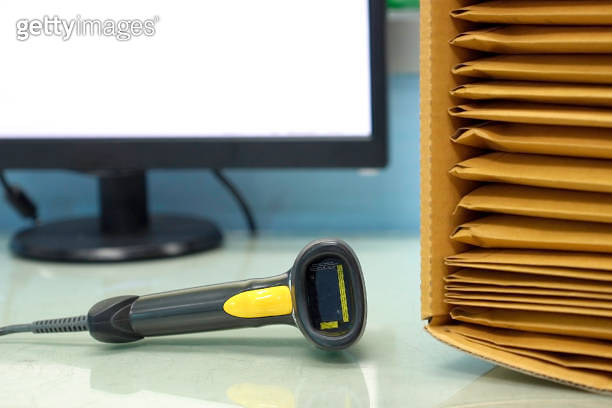 Barcode reader and stack of documents in brown envelops waiting to be ...