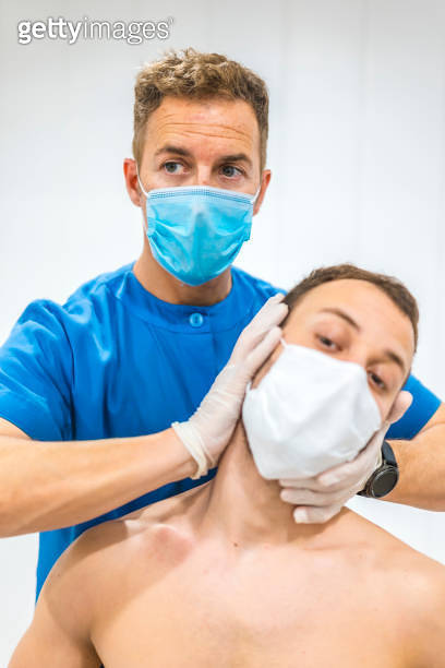 Giving a patient a neck massage. Physiotherapy with protective measures ...