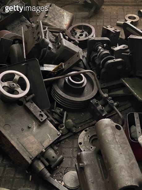 Broken parts from old metalworking machines thrown on the floor ...