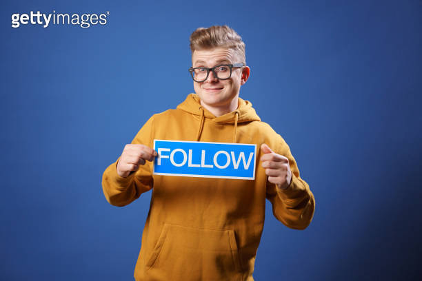 A vlogger in the studio records content. A young man holds a sign ...