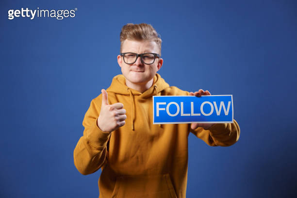 The video blogger shows a thumbs-up gesture with one hand, and holds a ...