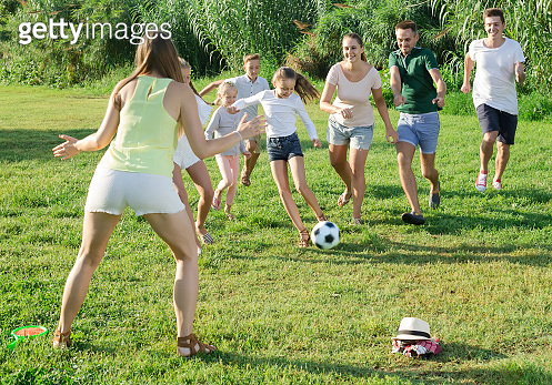 Two friendly families with children playing football in nature at ...