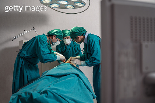 Surgeons team performing surgery a seriously injured patient through ...