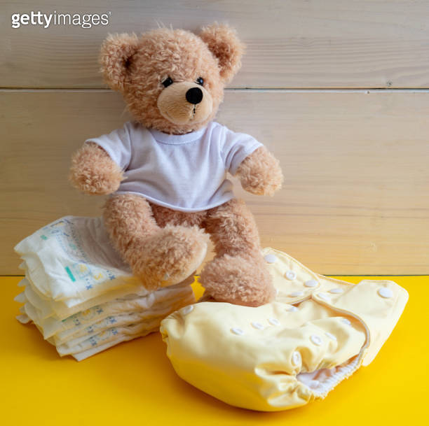 Baby diaper choice concept. Teddy sitting on cloth reusable nappy and ...