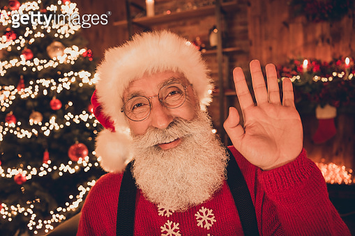 Portrait of attractive cheerful Santa waving hello congrats eve party ...