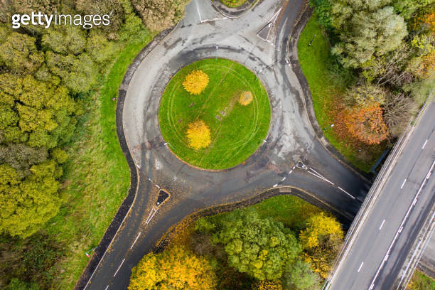 Aerial view of a small traffic roundabout with trees displaying full ...