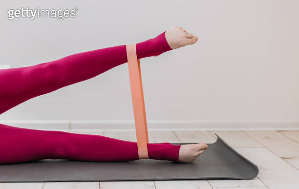 Athletic young woman makes side bar. Girl warms up legs, using fitness ...