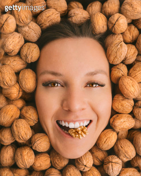 Happy smiling woman face on a walnuts background. Eating nuts. Healthy ...
