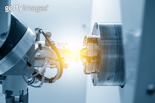 The robotics arm gripping the metal part from CNC lathe machine with ...