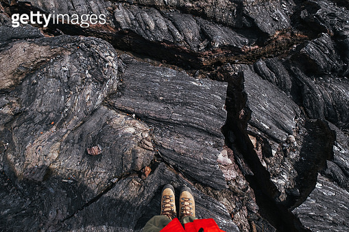 legs of traveler walking on the frozen lava of volcano. Hike in the ...