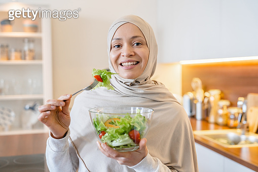 Muslim islamic arabian woman wife in hijab eating vegetable salad in ...