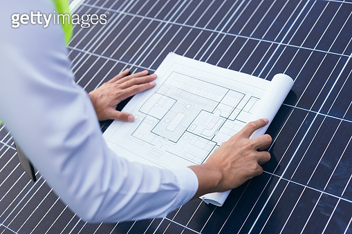 Engineer open blueprint of solar farm project on solar cells panel ...